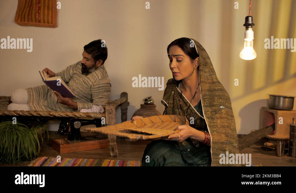Attractive village lady in Saree cleaning rice in a traditional bamboo ...