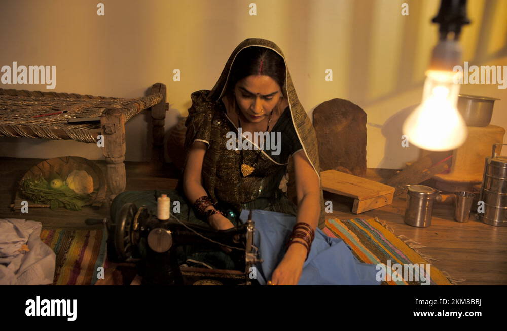 An Indian woman from a village stitching clothes on her old sewing ...