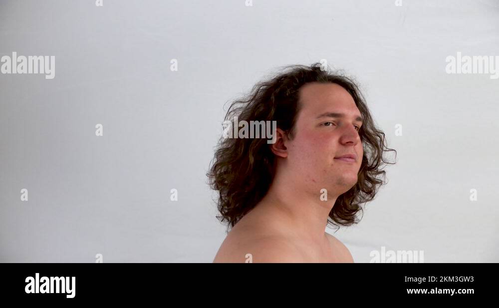 closeup of shirtless young man turned to the left and shaking his hair ...