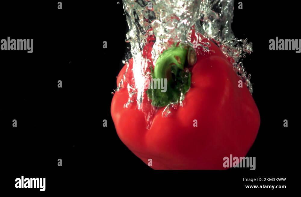 Super slow motion red bell pepper falls under the water with air ...