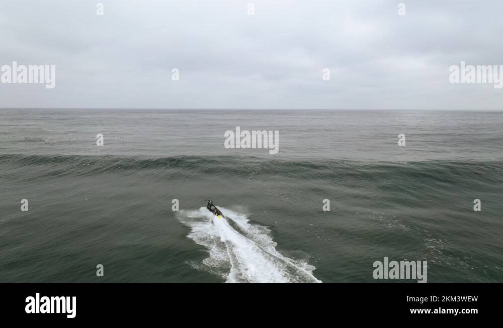Jet ski in the sea during a storm surge, rescuing a big wave surfer ...