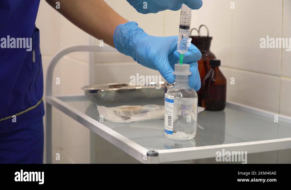 The doctor prepares a syringe with an injection and saline solution ...