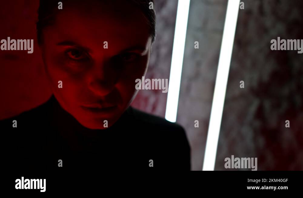 scary red light on face of adult woman in dark room, lady is looking at ...