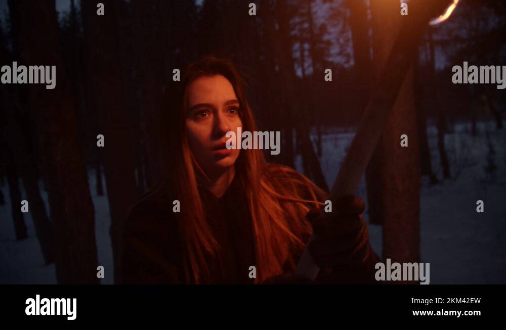 Young lost and scared woman with torch walking in the night forest ...