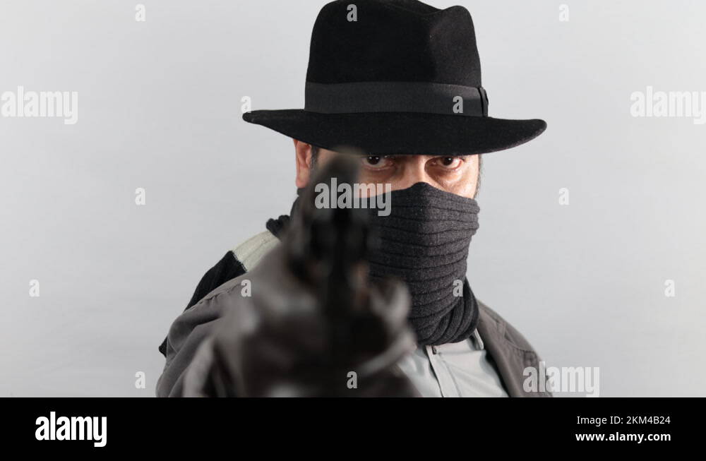 Gangster, bandit or cowboy with covered face pointing the gun at the ...