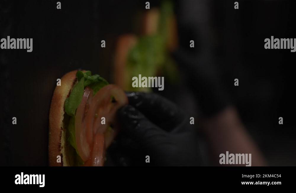 Preparing burgers in slow motion with black background. Chef cooking in ...