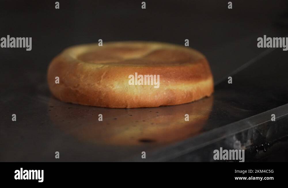Chef toasting a burger bun with butter. Cook turns burger bun over ...