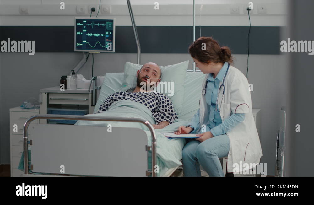 Sick man resting in bed with oxygen tube talking with doctor explaining ...