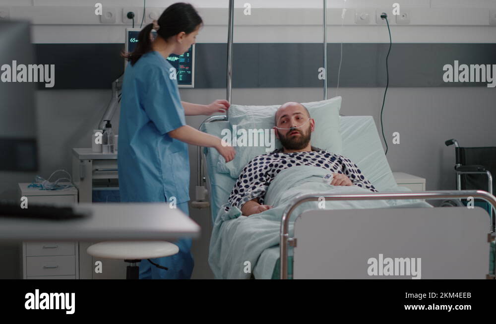 Practitioner asisstant arrange patient bed to sick man during sickness ...