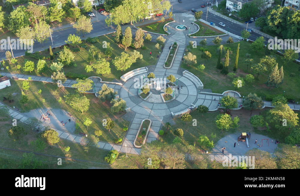 Park - round paved playground in a garden surrounded by trees and grass ...