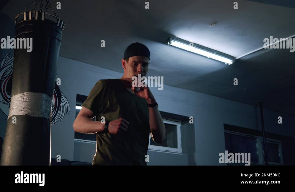 Alone boxer improves boxing movements in dark gym in slow motion. Young ...