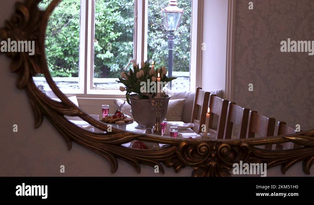 Camera moves across an antique mirror to show the dining table in a ...