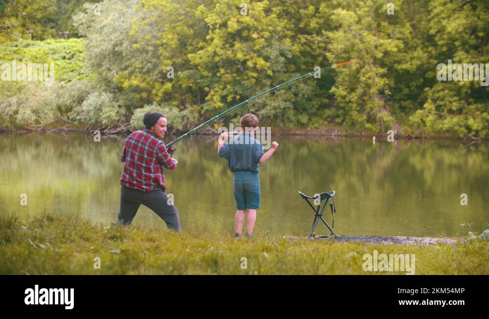 Two brothers on fishing - man pulling the rod and his little brother ...