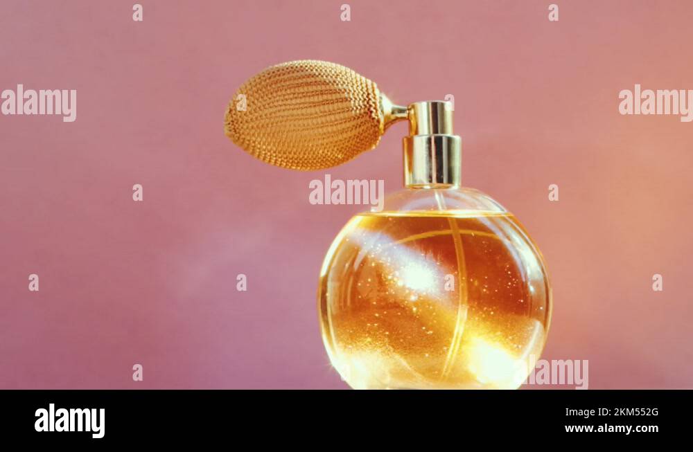 Luxury golden perfume bottle and shining light flares on pink ...