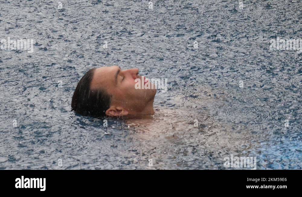 Man stand at water, turn face up to heavy rain, slow motion shot Stock ...