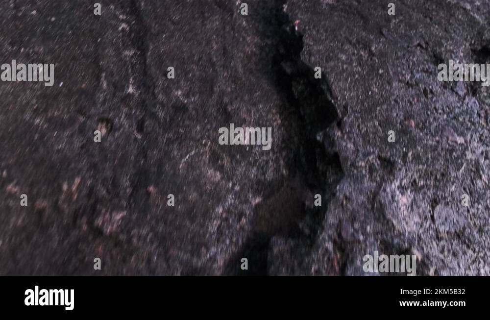 deep crack in an old black cement stone wall. stone texture background ...