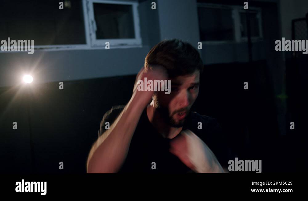 Alone boxer improves boxing movements in dark gym in slow motion. Young ...