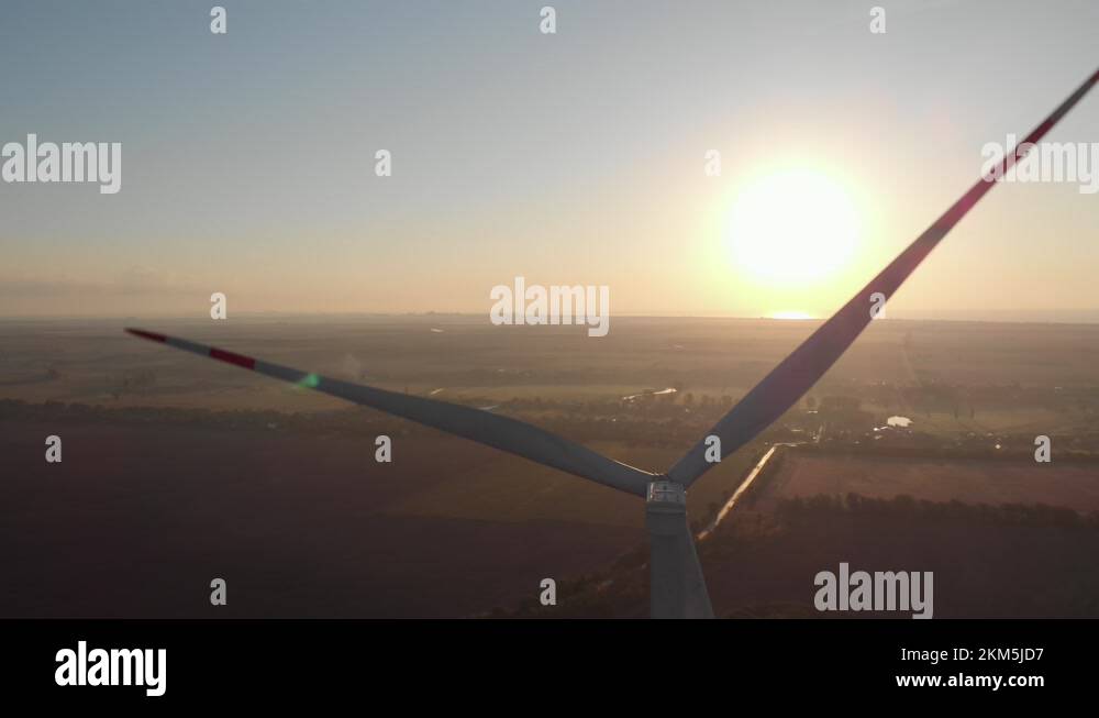 Aerial wind power turbine rotor blades backlight by sunset beam rays ...