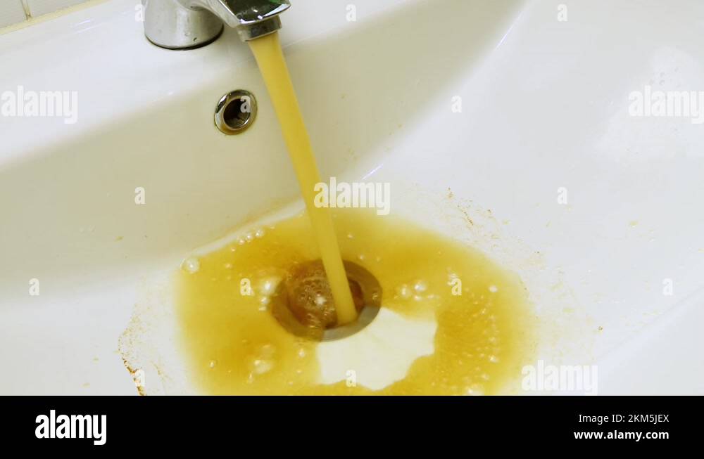 Close up dirty rusty brown polluted water flowing from tap in bathroom ...