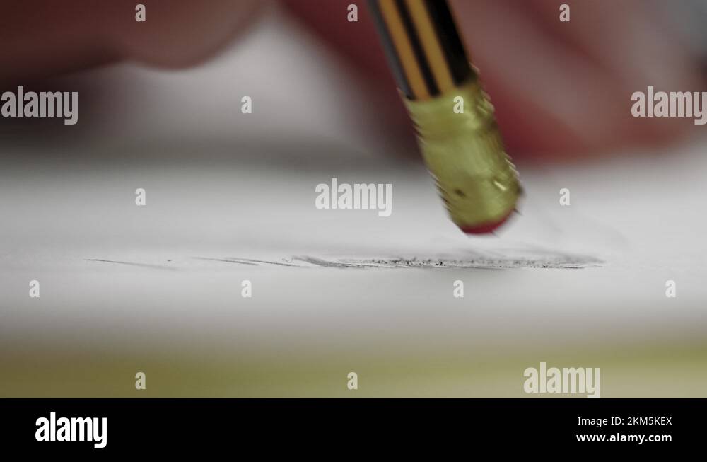 Close up - a man's hand with a pencil and an eraser erases what is ...