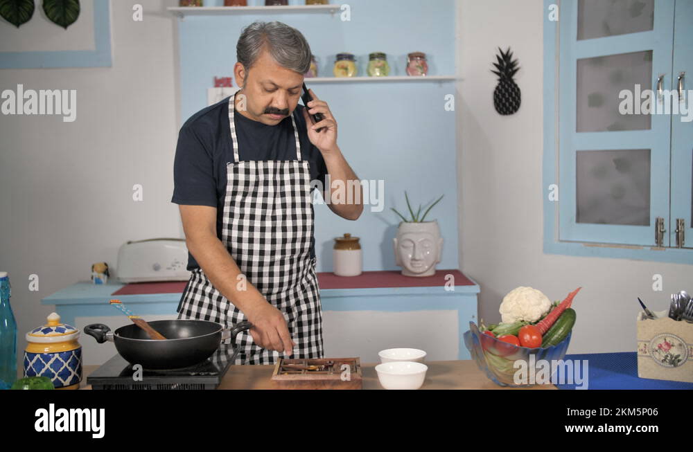Professional Indian male cook adding spices to his food - home-style ...