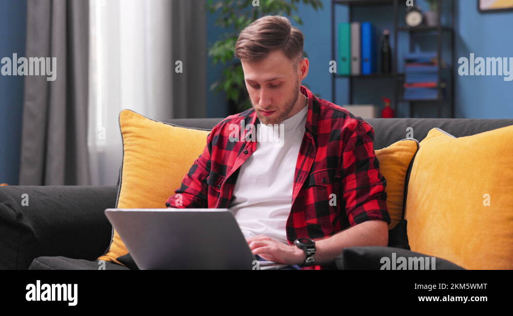 A handsome college student boy is studying remotely while sitting on ...