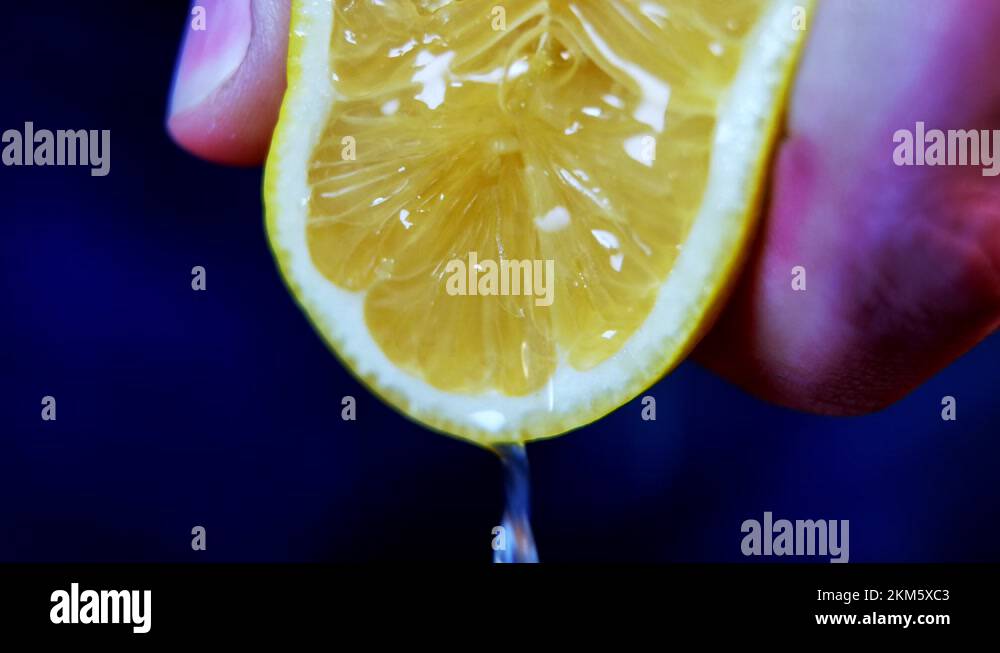 Hand squeezing out fresh orange. Citrus juice drains from the pulp and ...