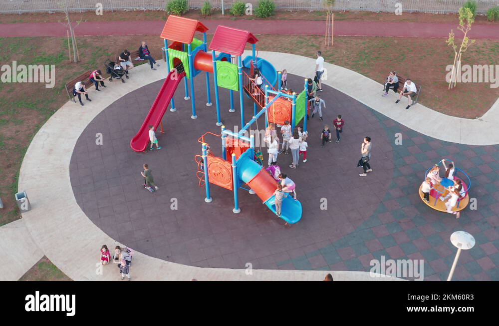Playground for kids in a park, busy with excited and joyful children ...
