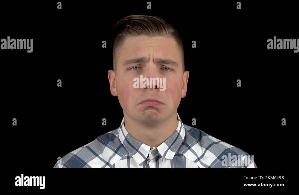 A young man takes off his mask and shows an emotion of sadness on his ...