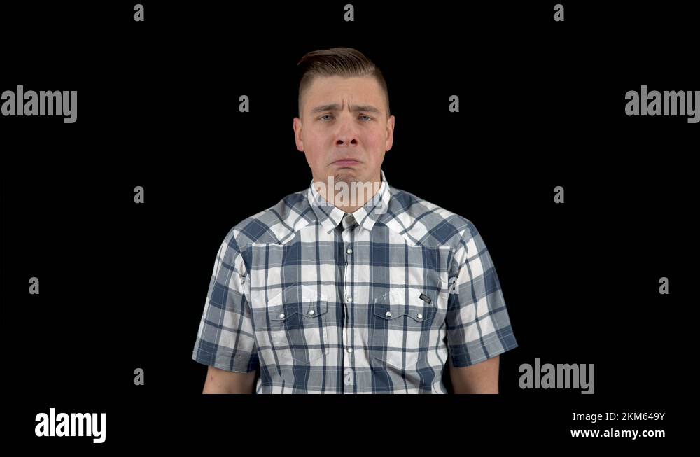A young man takes off his mask and shows an emotion of sadness on his ...