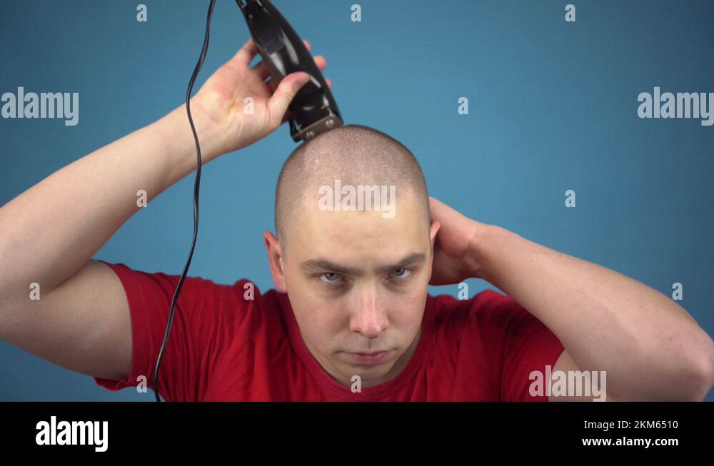 The bald young man insolently shaves his head. A man cuts his hair ...