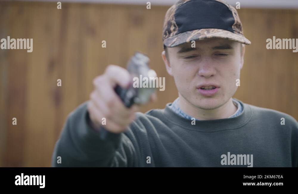 A teenager with a gun in his hands threatens. The man is aggressive and ...