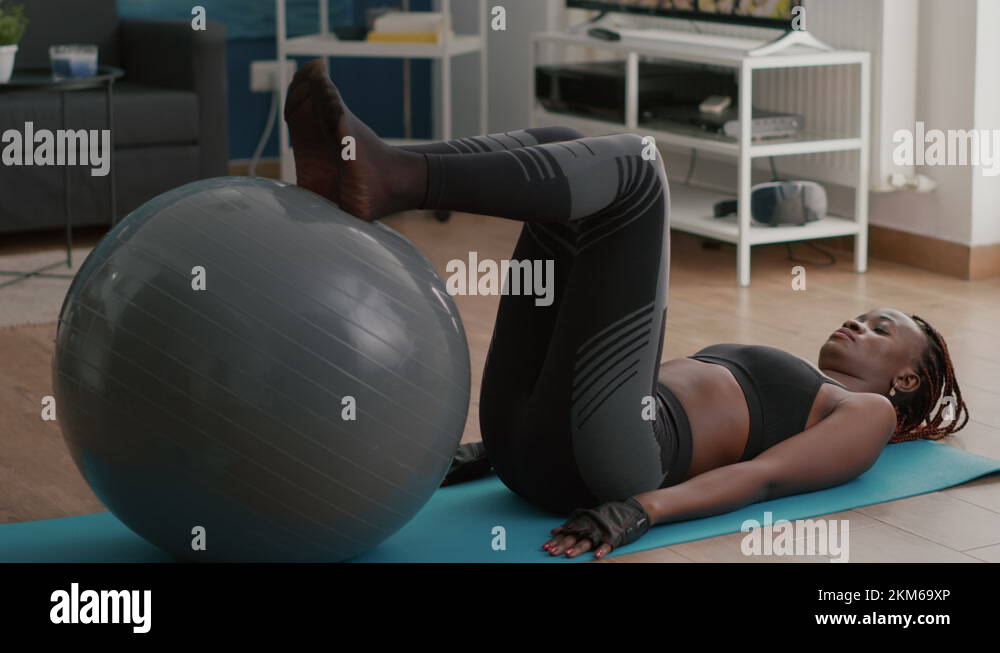 Fit woman with black skin doing abs exercise using fitball flexing ...