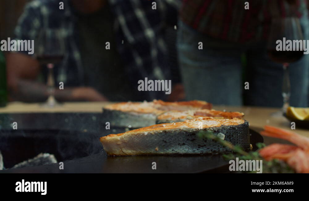 Woman chef salting fish on grill outside. unknown woman pouring salt on ...