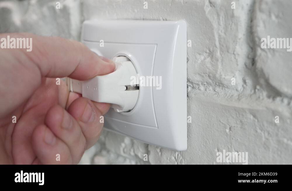Inserting an Electrical Power Cord into a Socket on the Office Wall ...