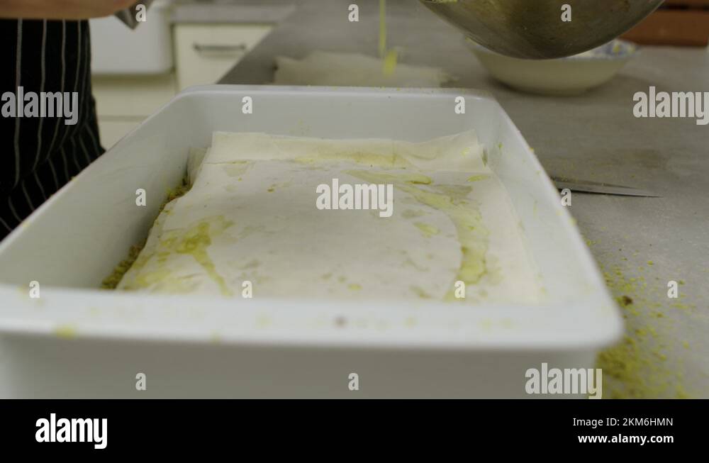 Adding melted butter onto baklava dough layer inside ceramic pan Stock ...