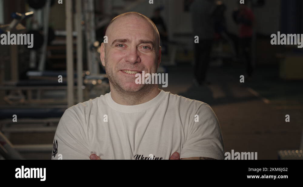 Paralympian man with defective legs sitting in a wheelchair in the gym ...