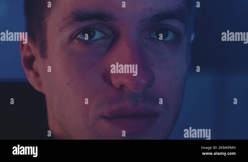 Close-up portrait of young guy watching movie tv film at night ...