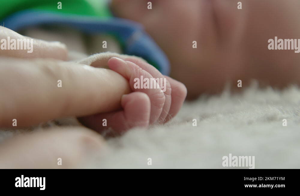 The hand of a sleeping newborn baby holding on to a parent's finger ...