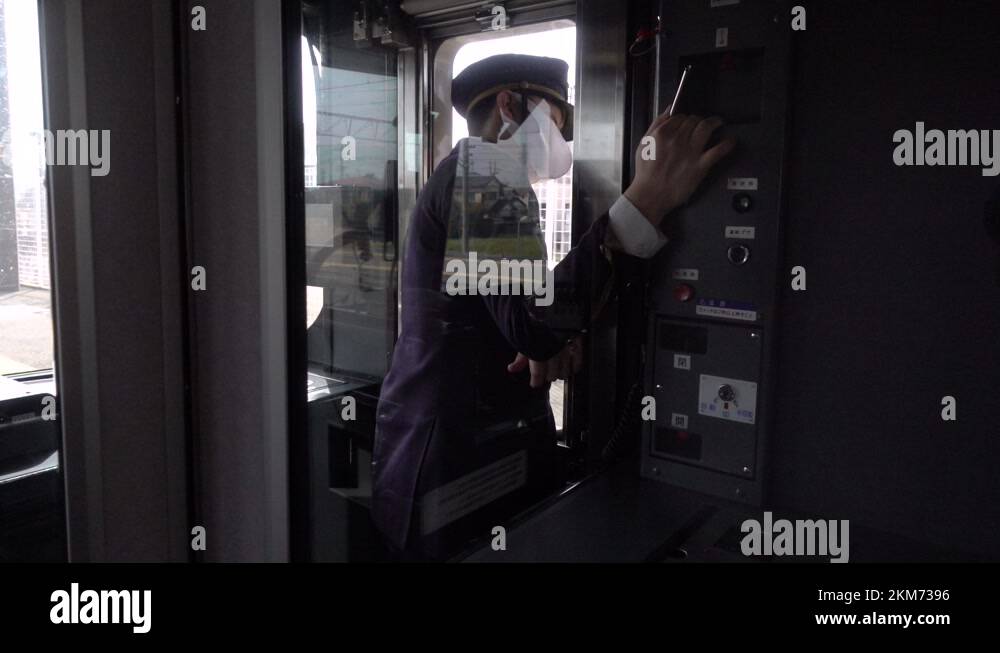 Interior view of train conductor at window with train driving into ...
