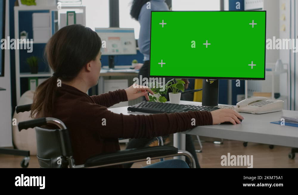 Invalid woman emplyee working on desktop computer green mock-up screen ...