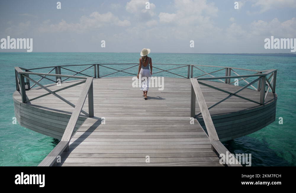 Female on wooden pier arms in the air, Young woman travelling in the ...