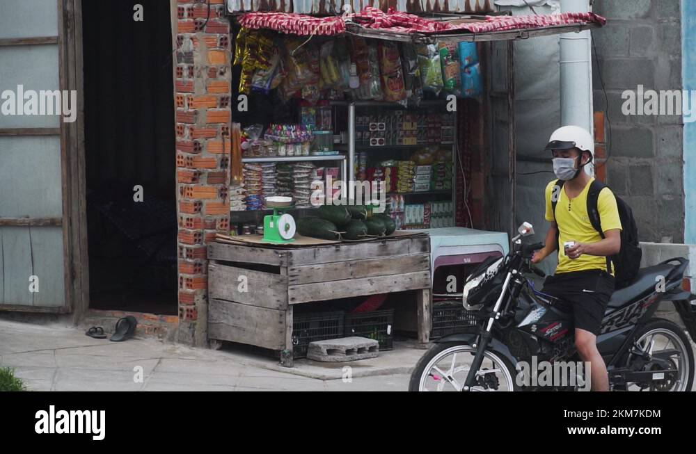 Boy on motorbike with helmet and protective mask near typical kiosk ...