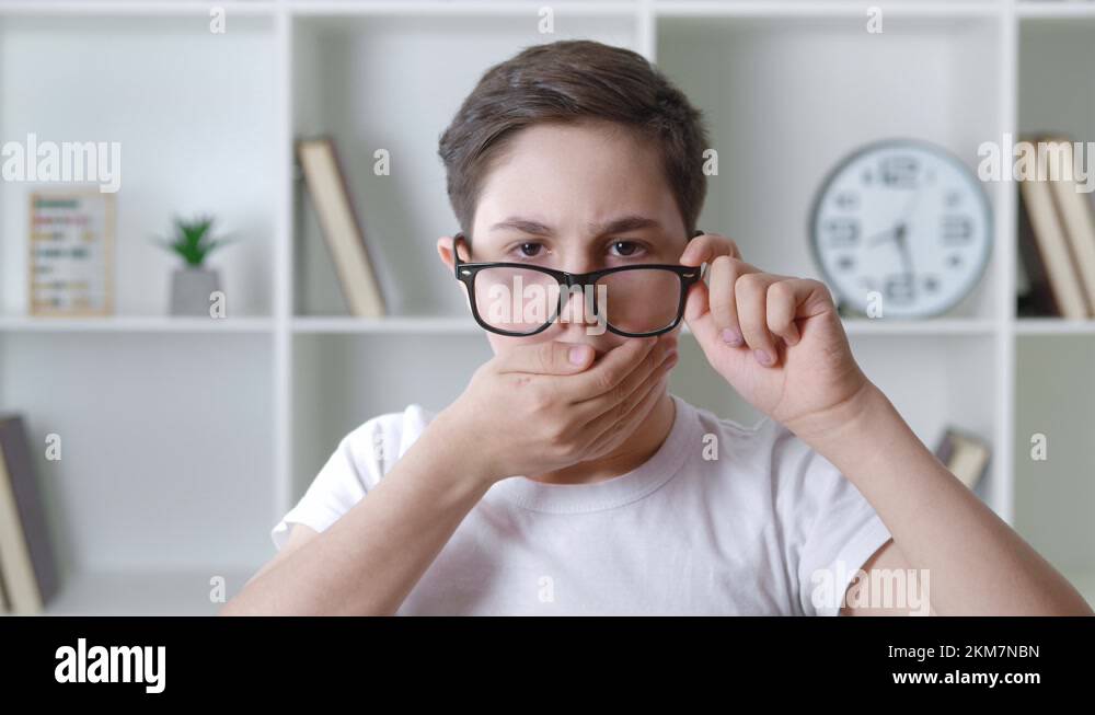 Afraid and shocked boy 13 years old in white shirt takes off glasses ...
