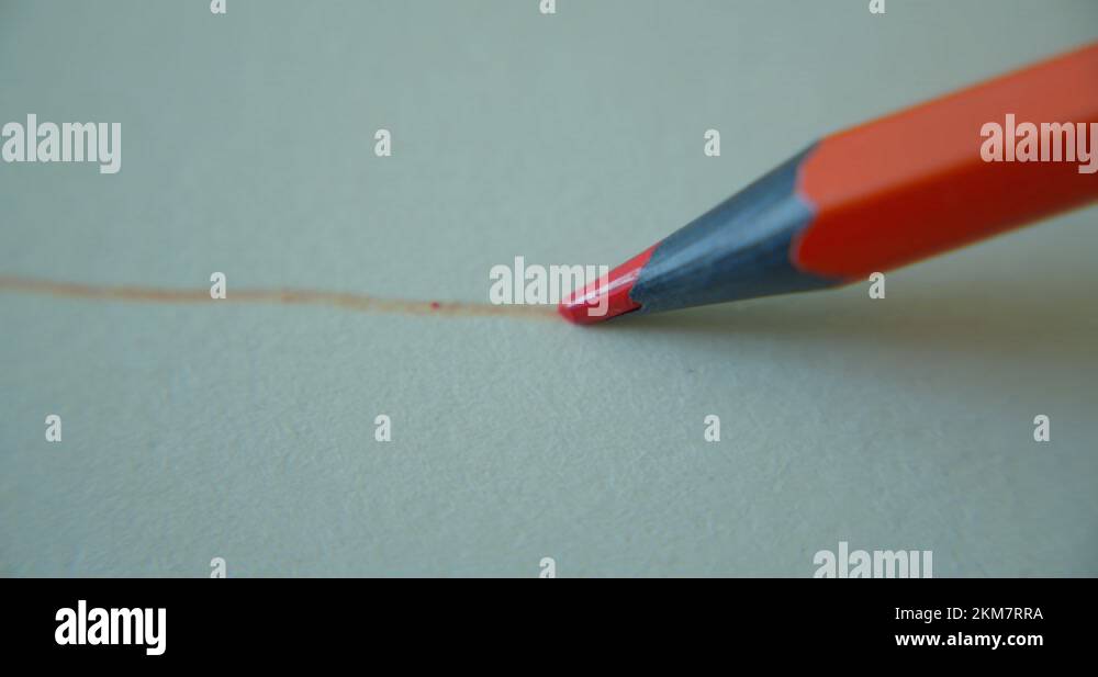 Graphite orange color pencil draws a straight line on a white ...