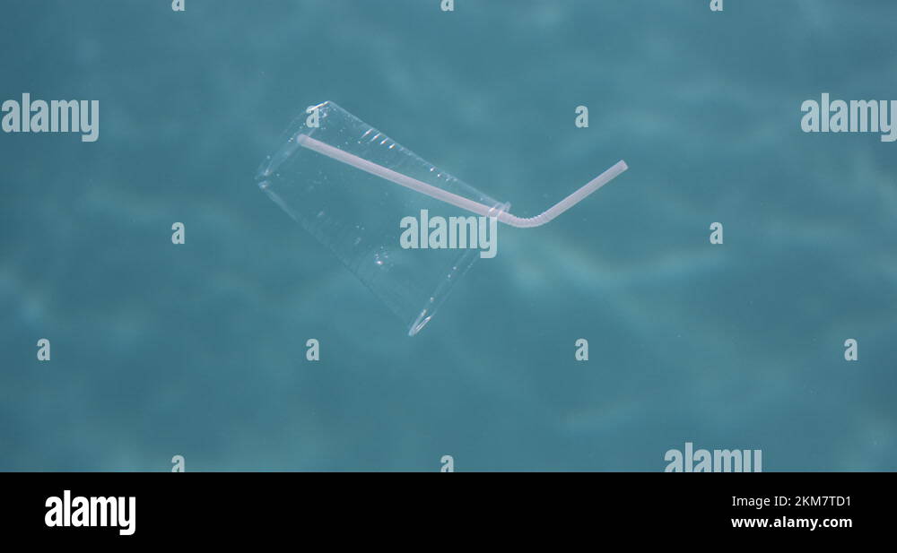 Underwater plastic. Close-up discarded single use cup with straw ...