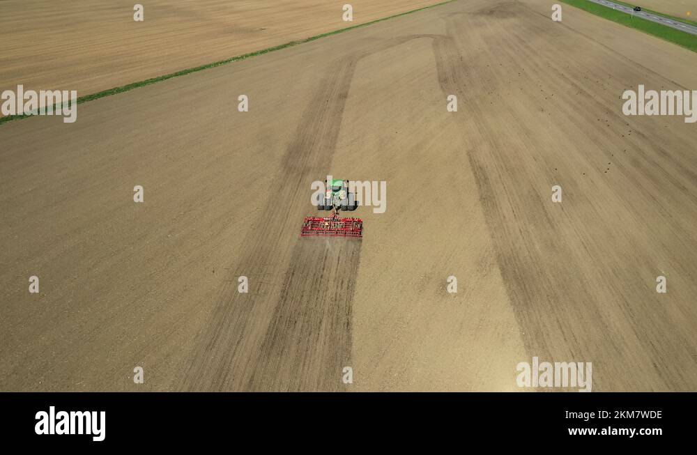 Tracking aerial view of green double wheeled tractor cultivating Stock ...