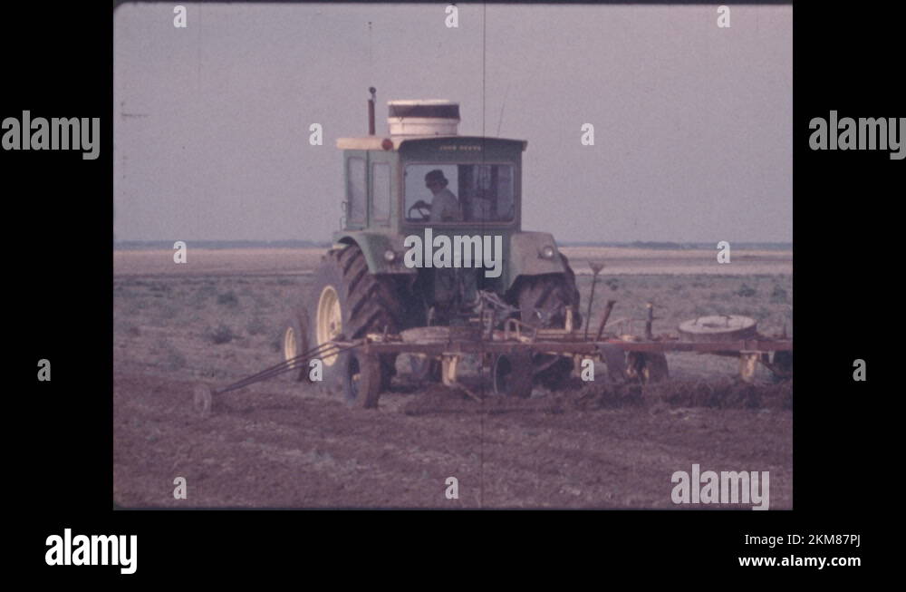1970s: Tractor pulling plow, zoom out. Tractor wheels driving, plow ...