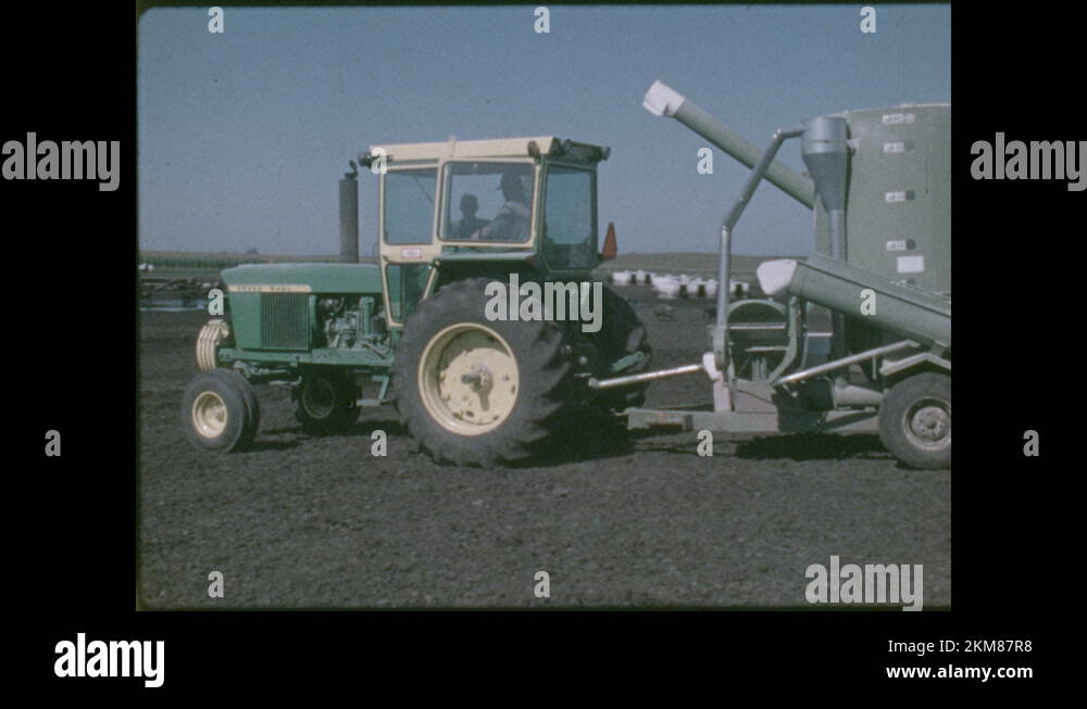 1970s: Tractor travels across field. Fields of crops on farm Stock ...