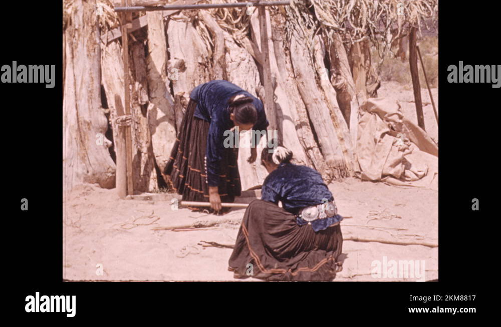 1950s: Two women stretch wool hung between two pieces of wood on ground ...